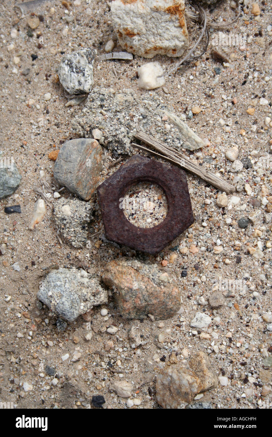 A red rusty nut surrounded by dirt sand rocks and pebbles Stock Photo ...