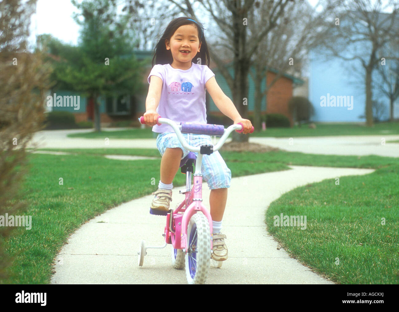 Asian girl riding bicycle on sidewalk Stock Photo - Alamy