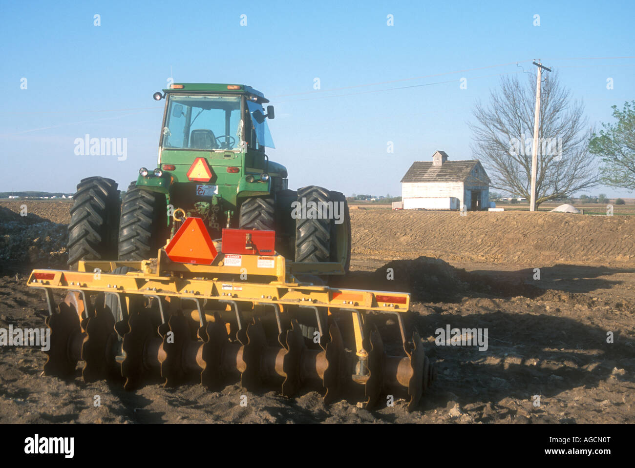 A John Deere tractor pulling a tiller in preparation for spring ...