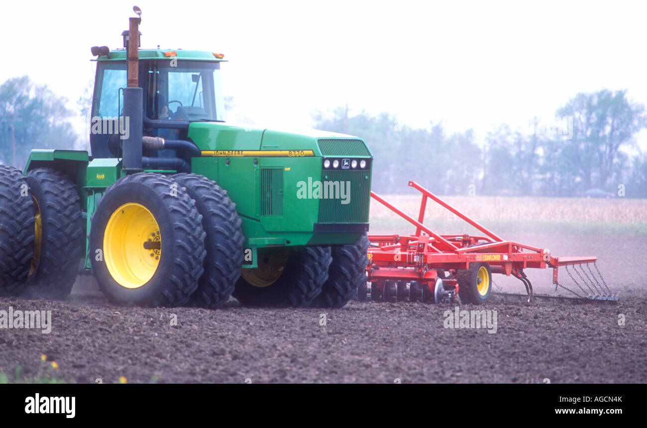 A John Deere tractor pulling a tiller in preparation for spring ...