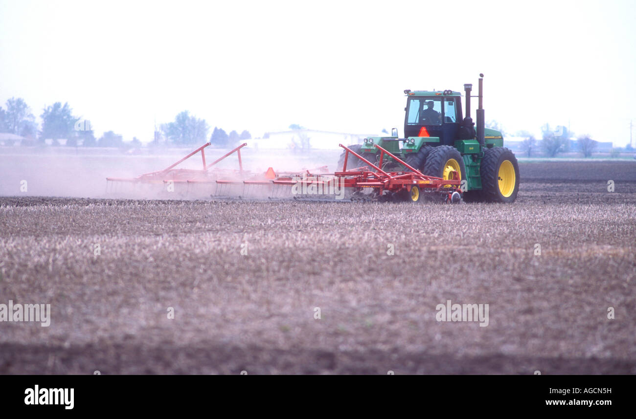 A John Deere tractor pulling a tiller in preparation for spring ...
