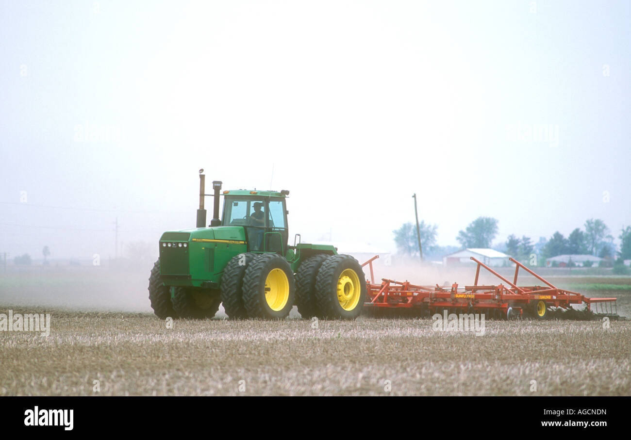 John Deere tractor tilling a farm field in spring to prepare for ...