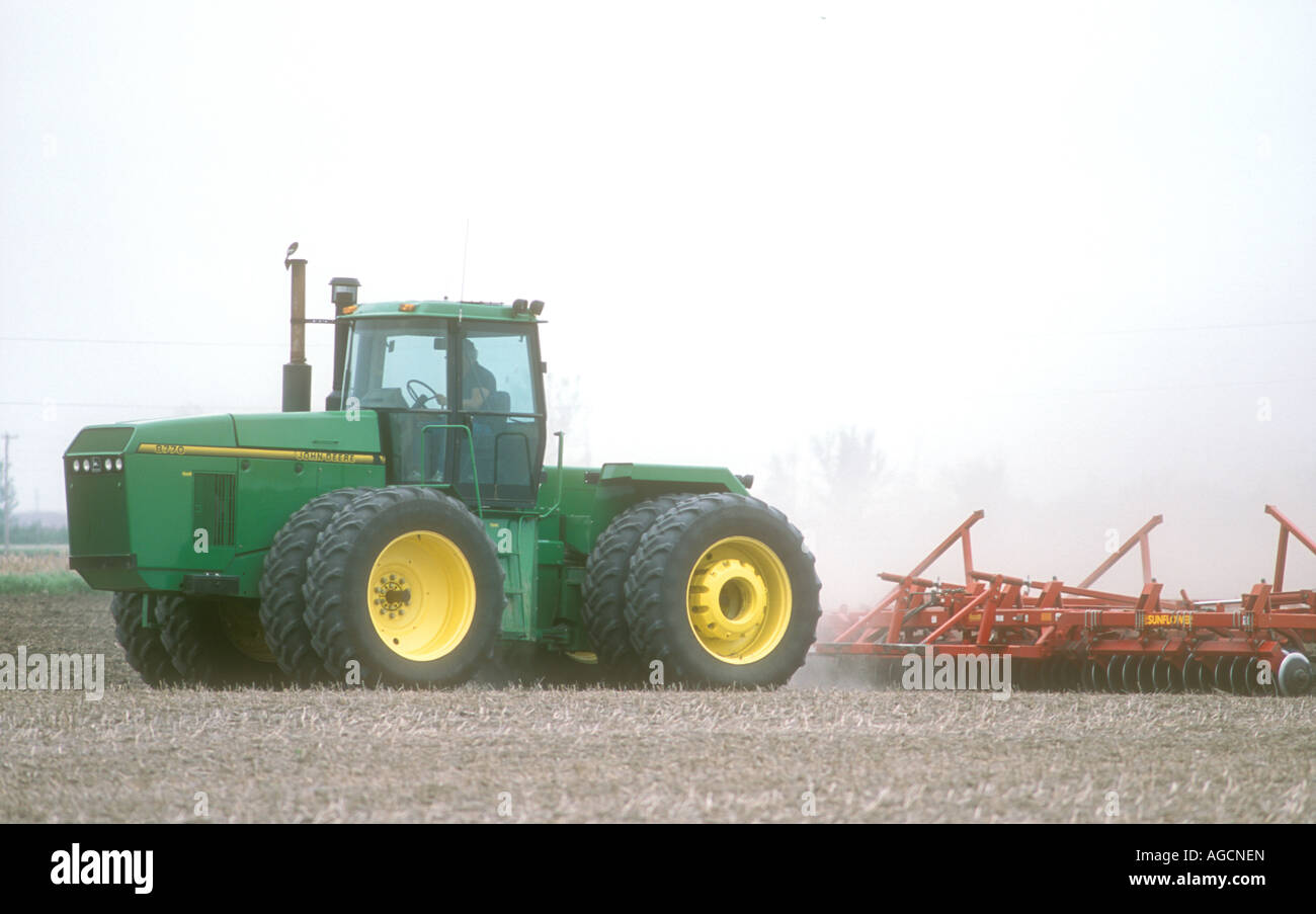 John Deere tractor tilling a farm field in spring to prepare for ...