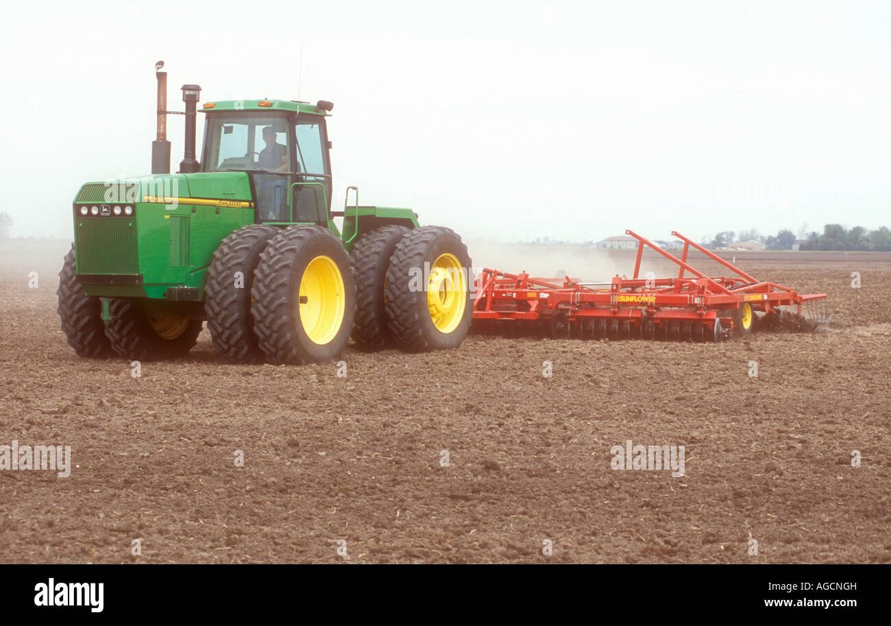 John Deere tractor tilling a farm field in spring to prepare for ...