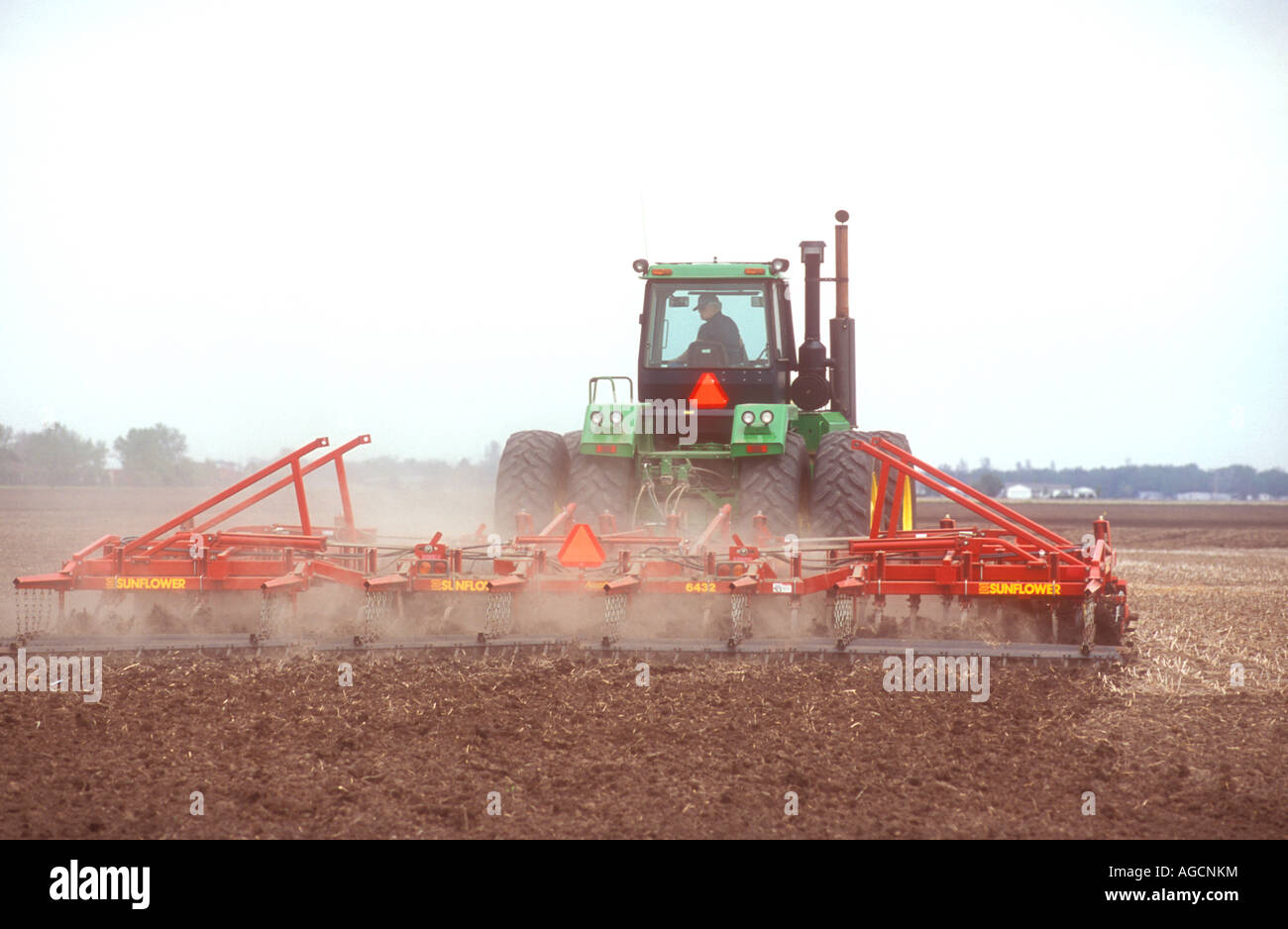 John Deere tractor tilling a farm field in spring to prepare for ...