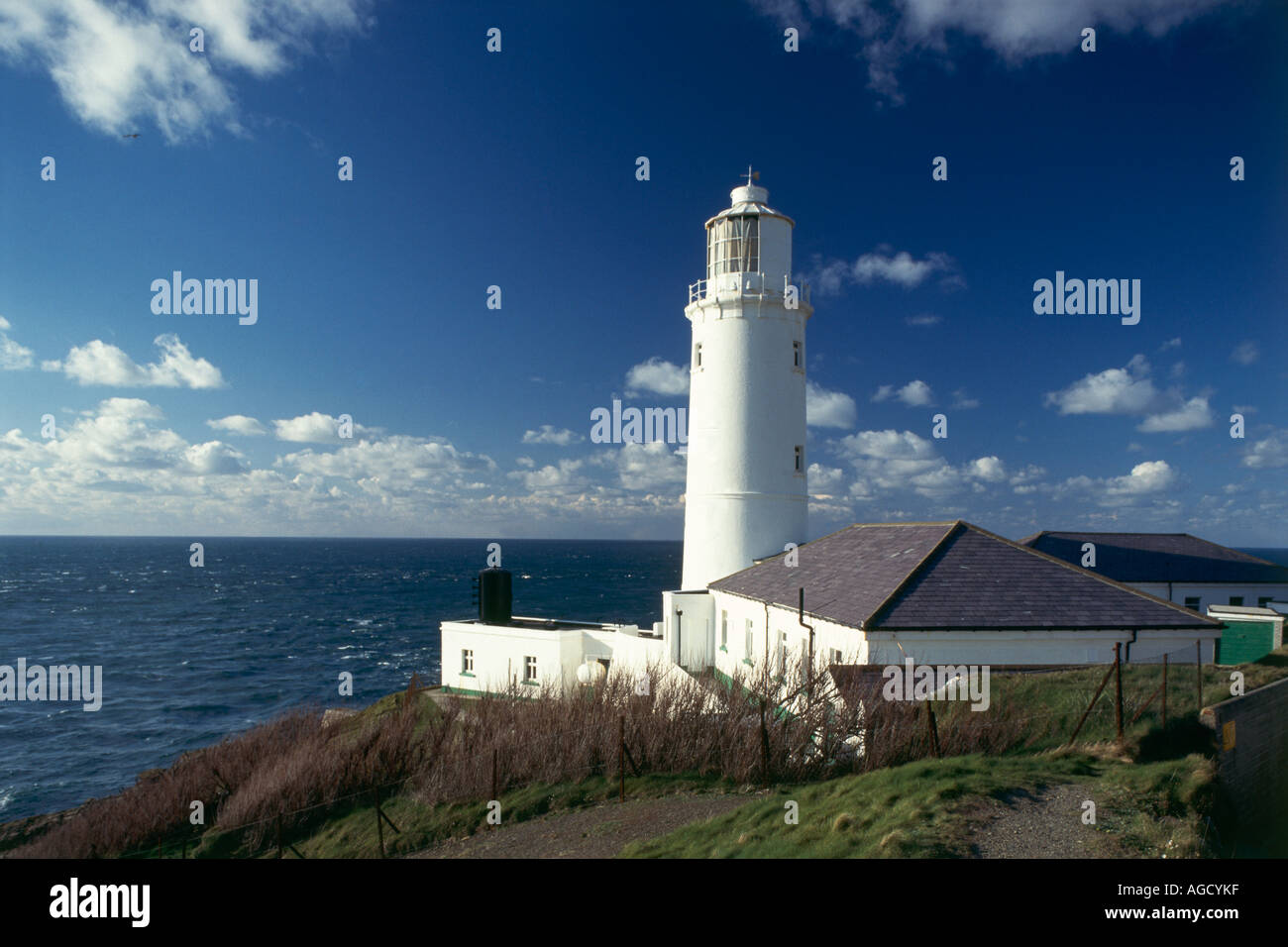 White lighthouse tower and attendant buildings looking out into the ...
