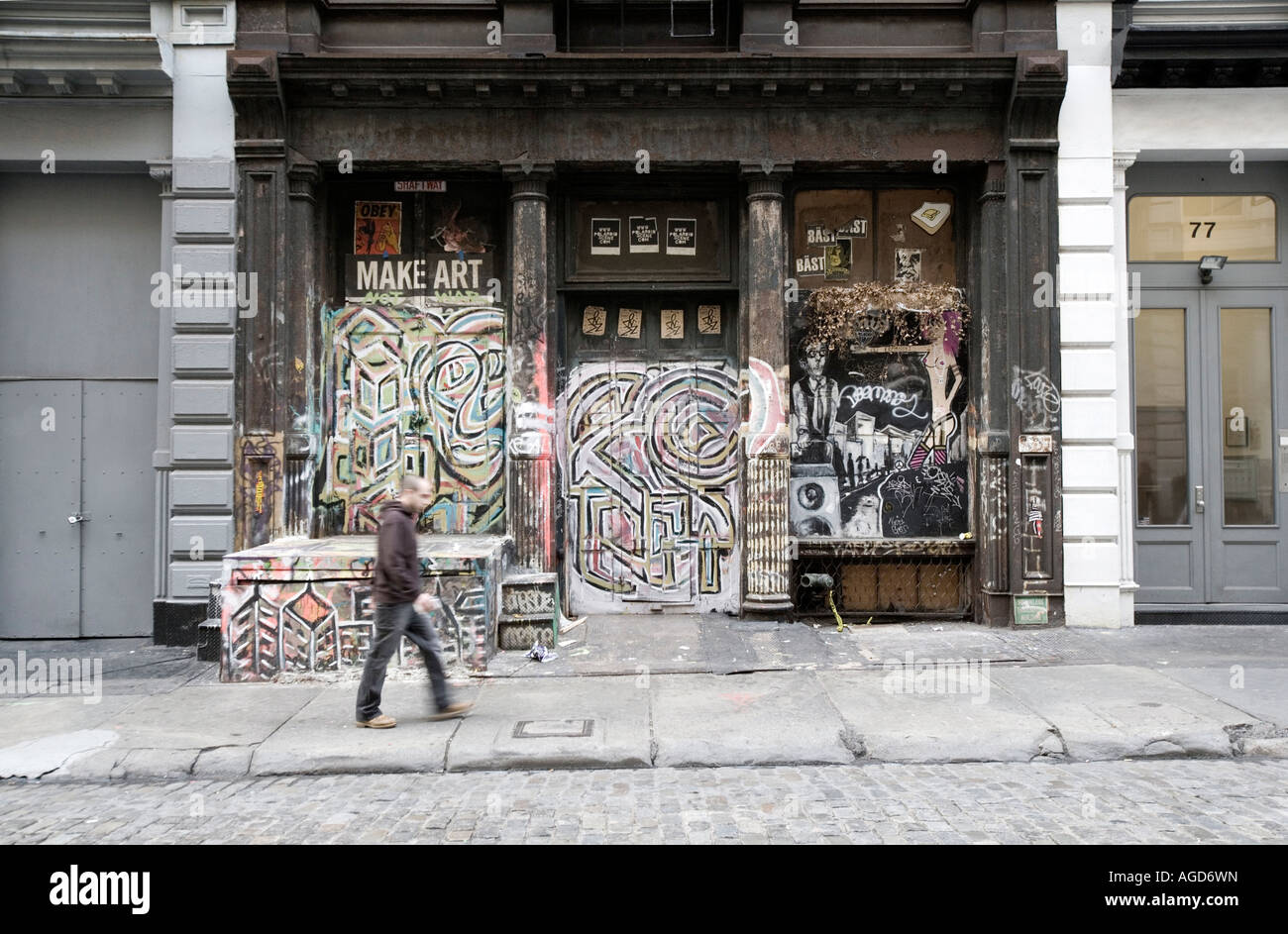 A pedestrian walking past a graffiti covered store that has been shut ...
