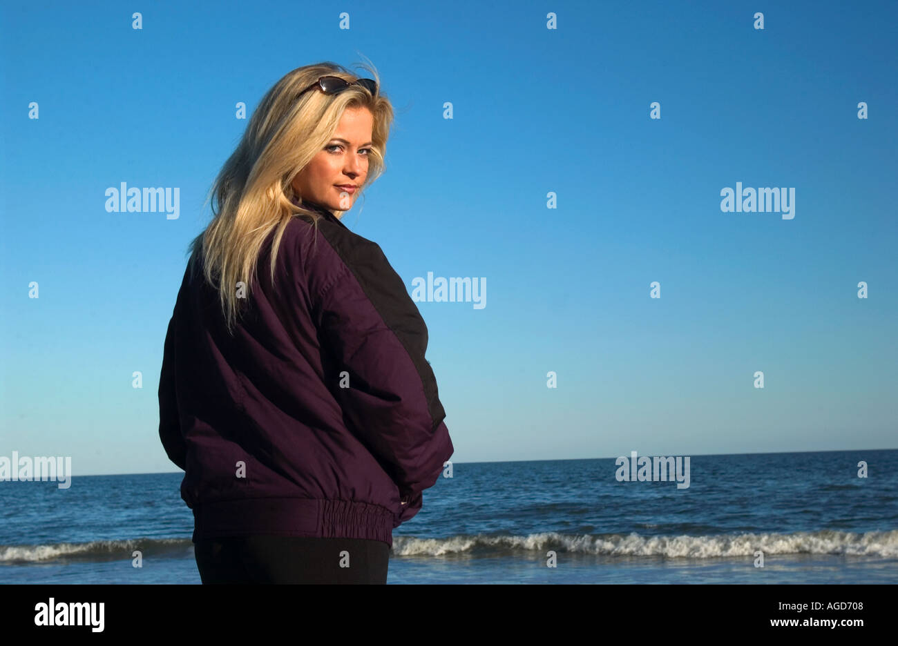 Pretty young blonde woman in her early 20s wearing a coat, glancing ...