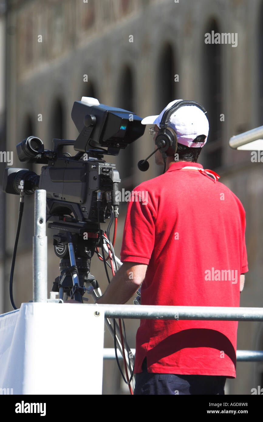A rear view shot of a television cameraman on a gantry with a modern ...