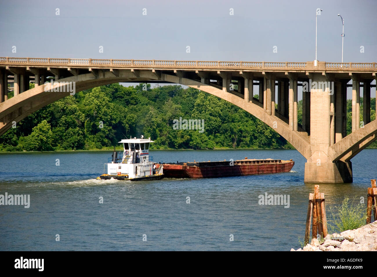 Tug boat and river barge pass under a bridge over the Arkansas River in ...