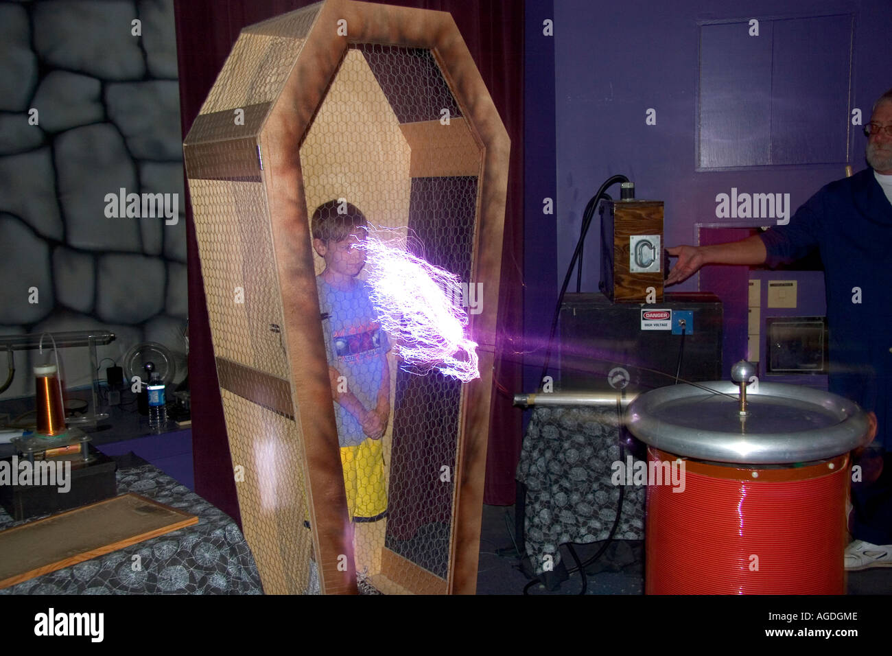 A boy in a wire cage demonstrating a Tesla coil with lightning at the ...