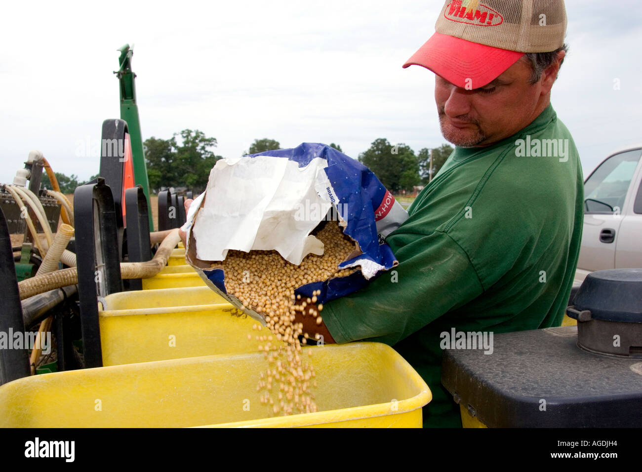 A farmer loading soy bean seeds into a planter in the east central ...