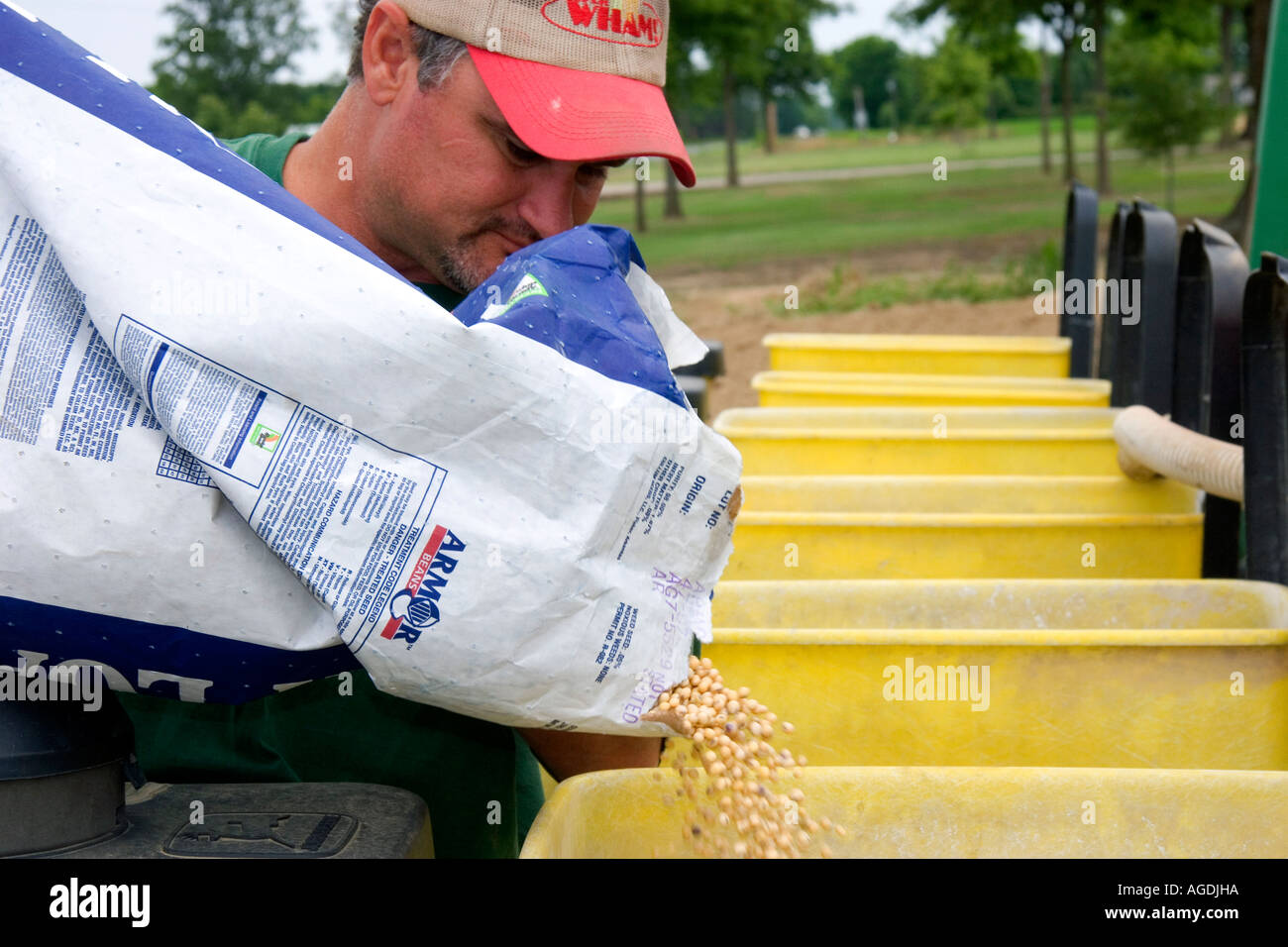 A farmer loading soy bean seeds into a planter in the east central ...