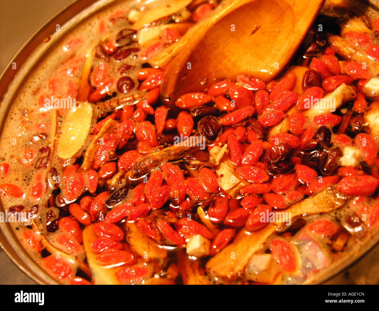 Traditional Chinese Medicine dried herbs boiling in pot stirred with ...