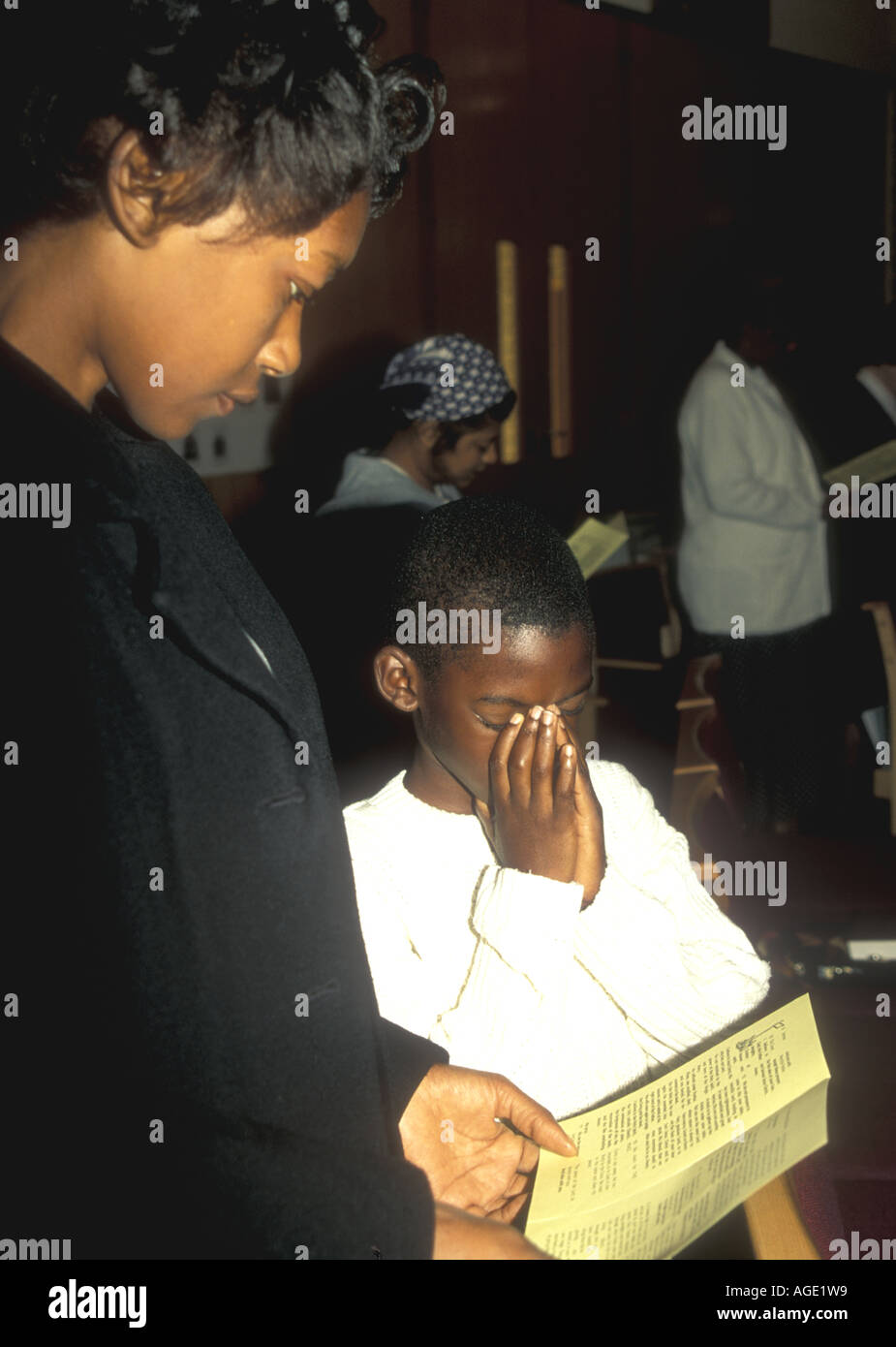 A young black Christian boy saying a prayer during a church service in ...