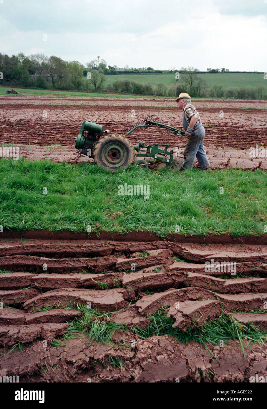 A farmer using a vintage petrol powered hand plough in a field in the ...