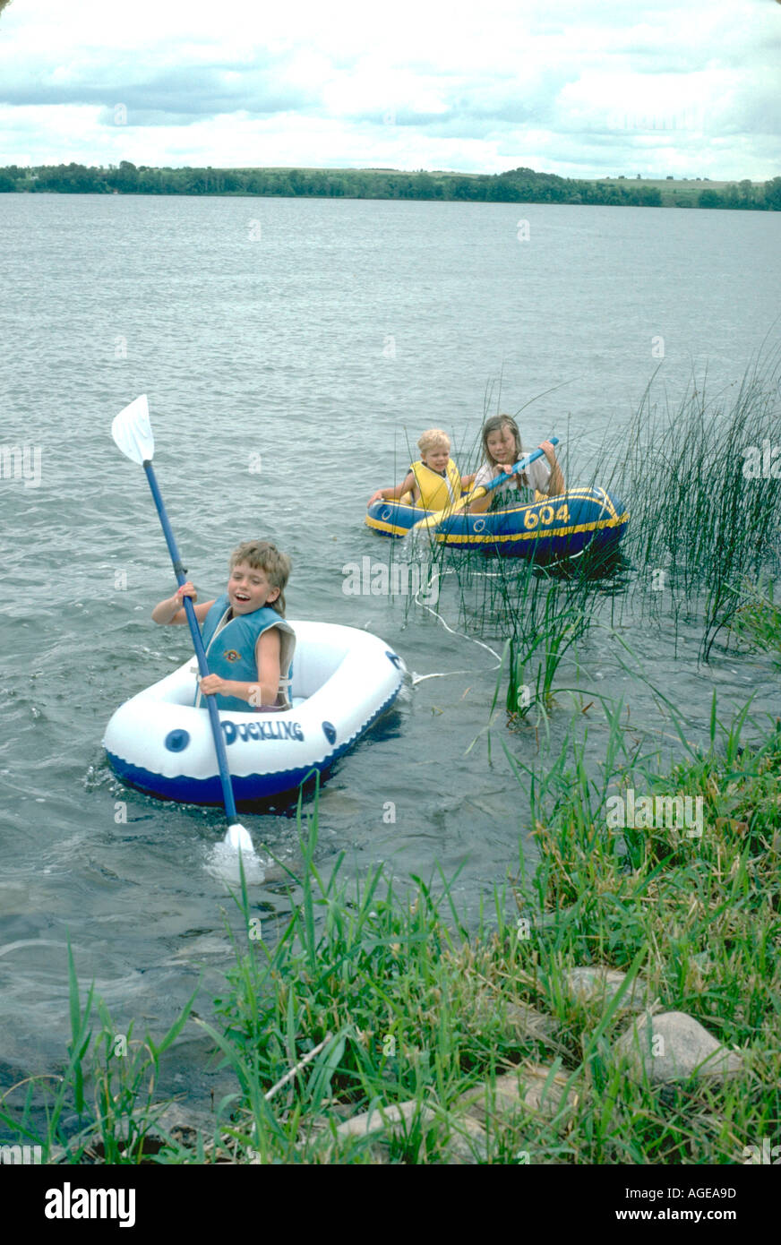 Children paddling inflatable rafts along shoreline ages 4 and 8 ...