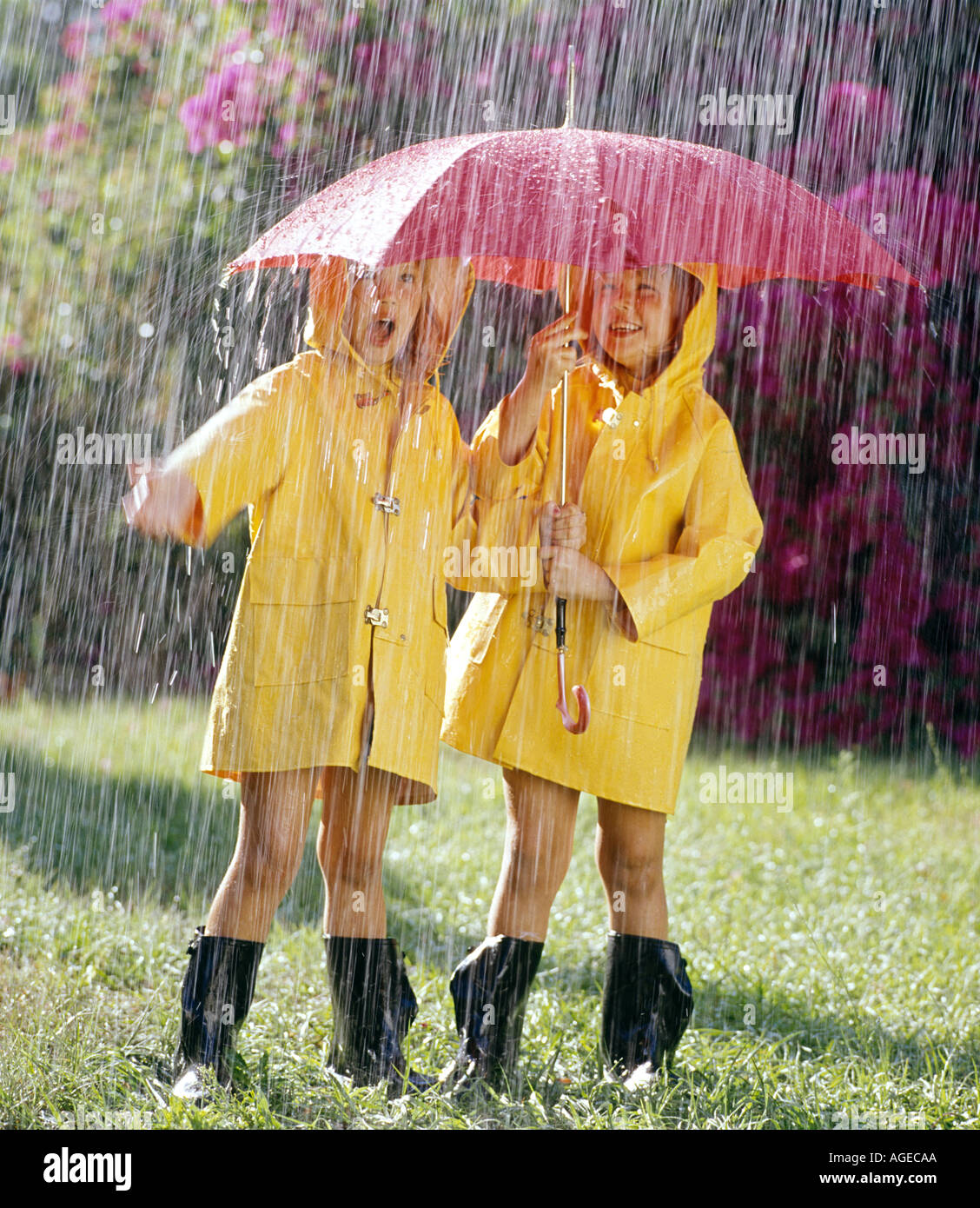 twin girls having fun in the rain with an umbrella and rain gear Stock ...