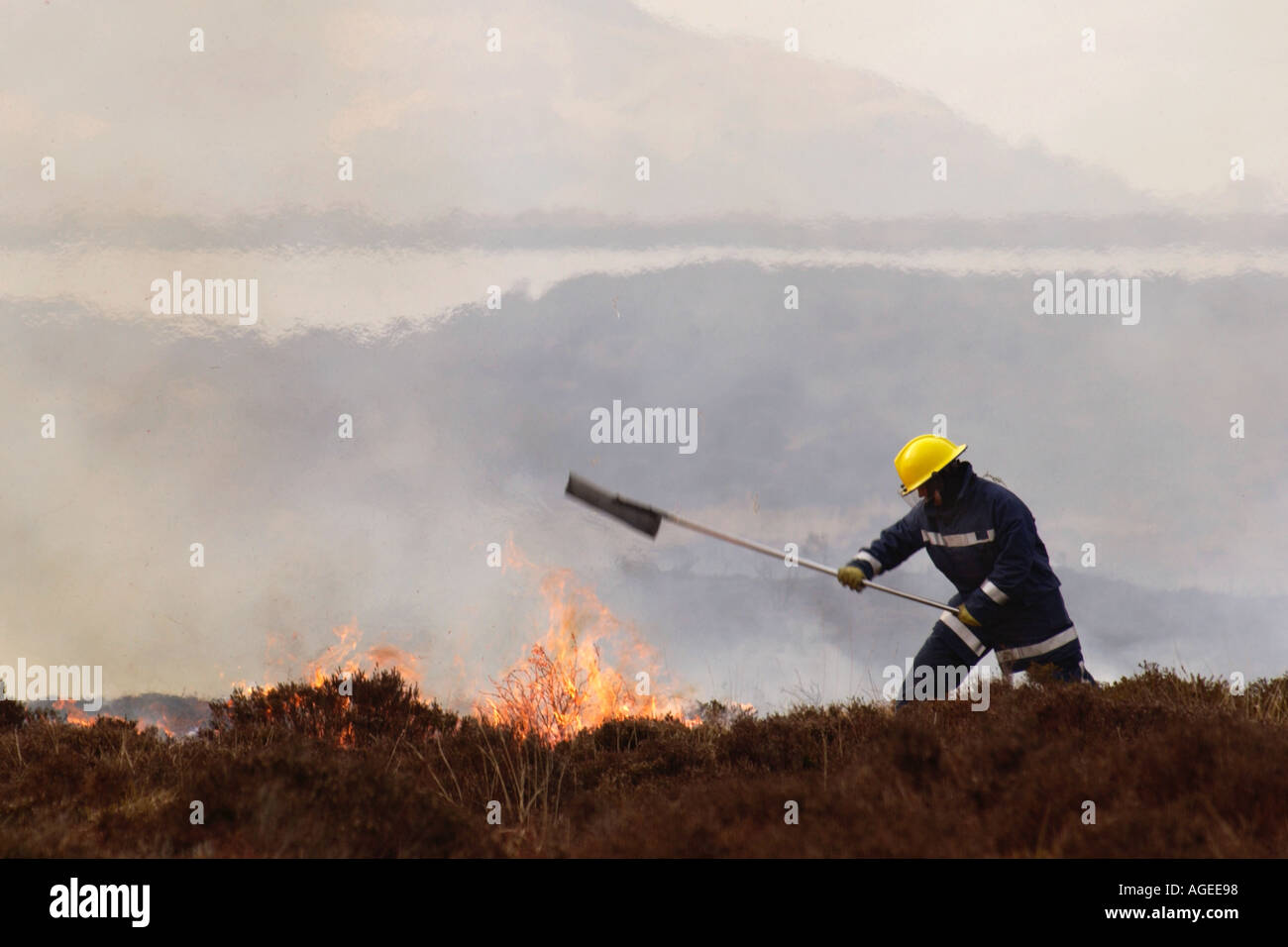 Fireman firefighter battles to control a fire on heather moorland in ...