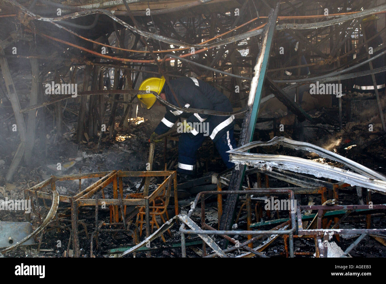 Firefighter sifting through the charred tangled remains of a classroom ...