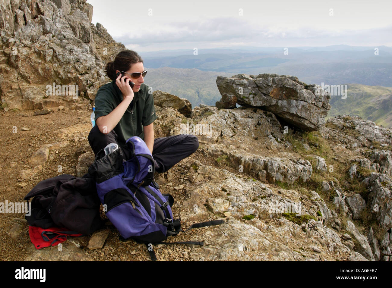 Young woman using a mobile phone on rock ledge while walking on Crib ...