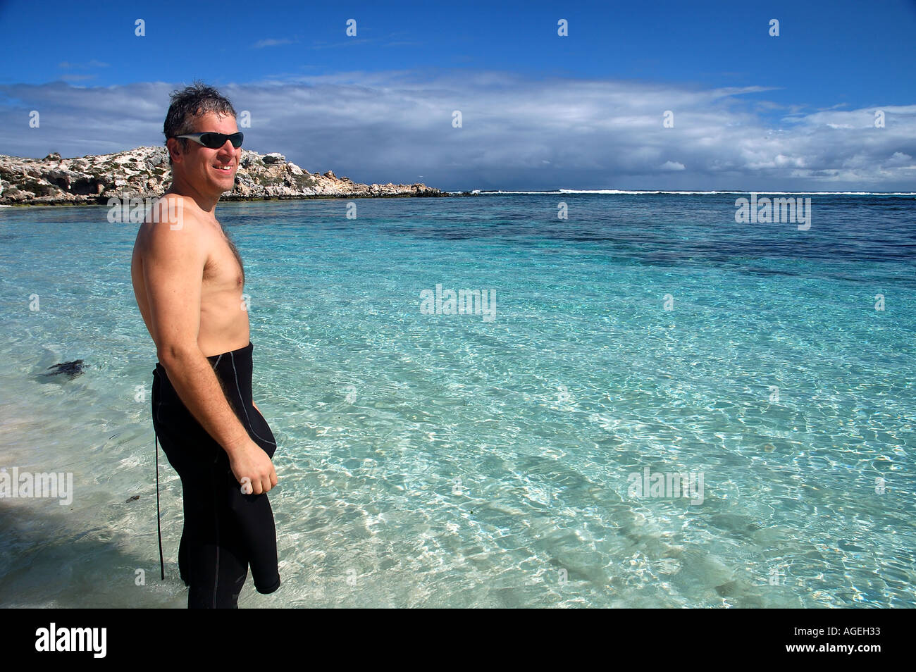 Man in half opened wetsuit standing in clear waters of Salmon Bay ...