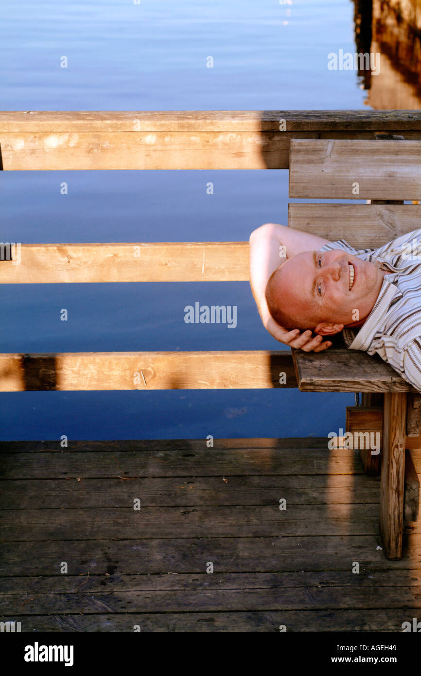 a man laying on a bench Stock Photo - Alamy