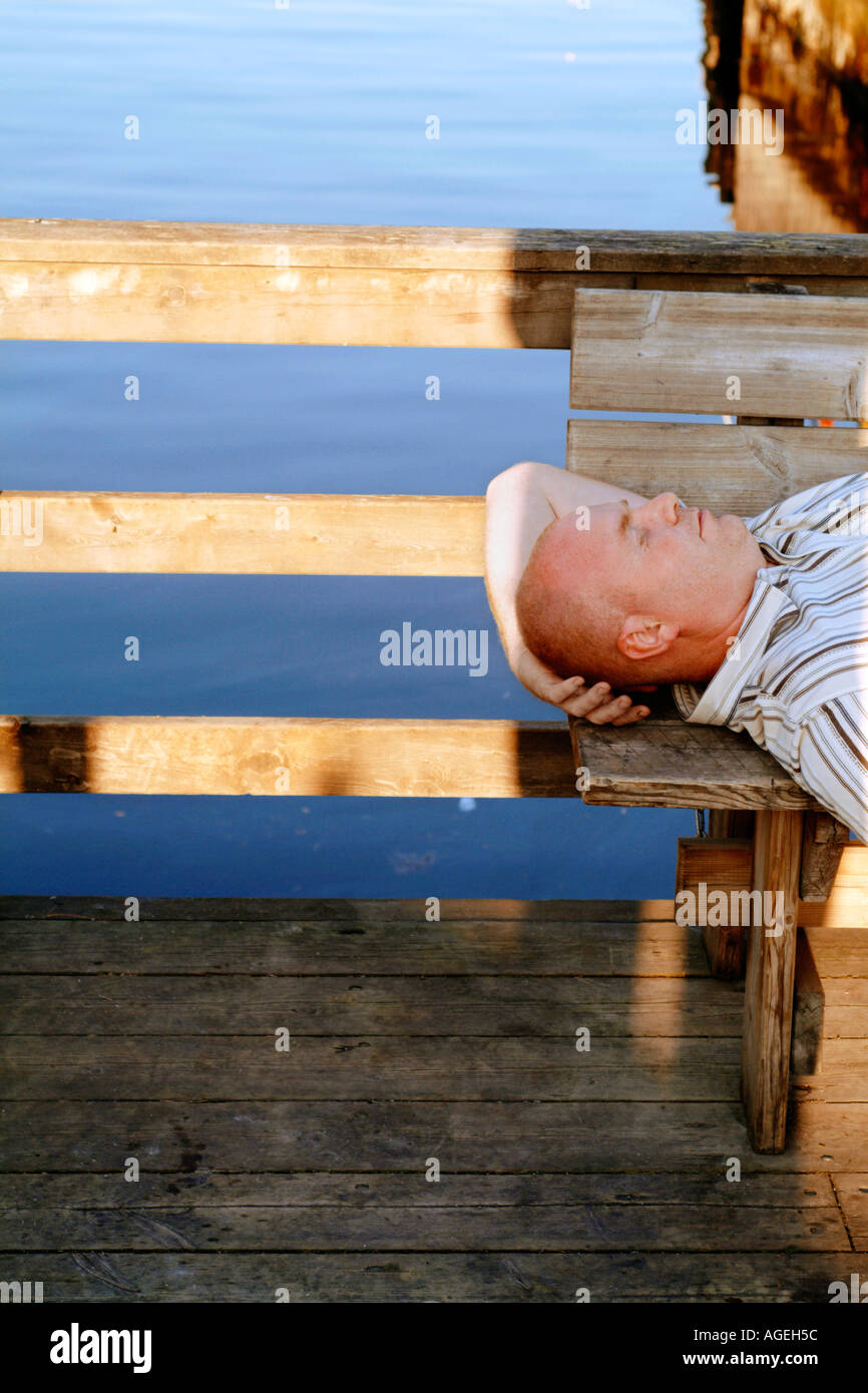a man laying on a bench Stock Photo - Alamy
