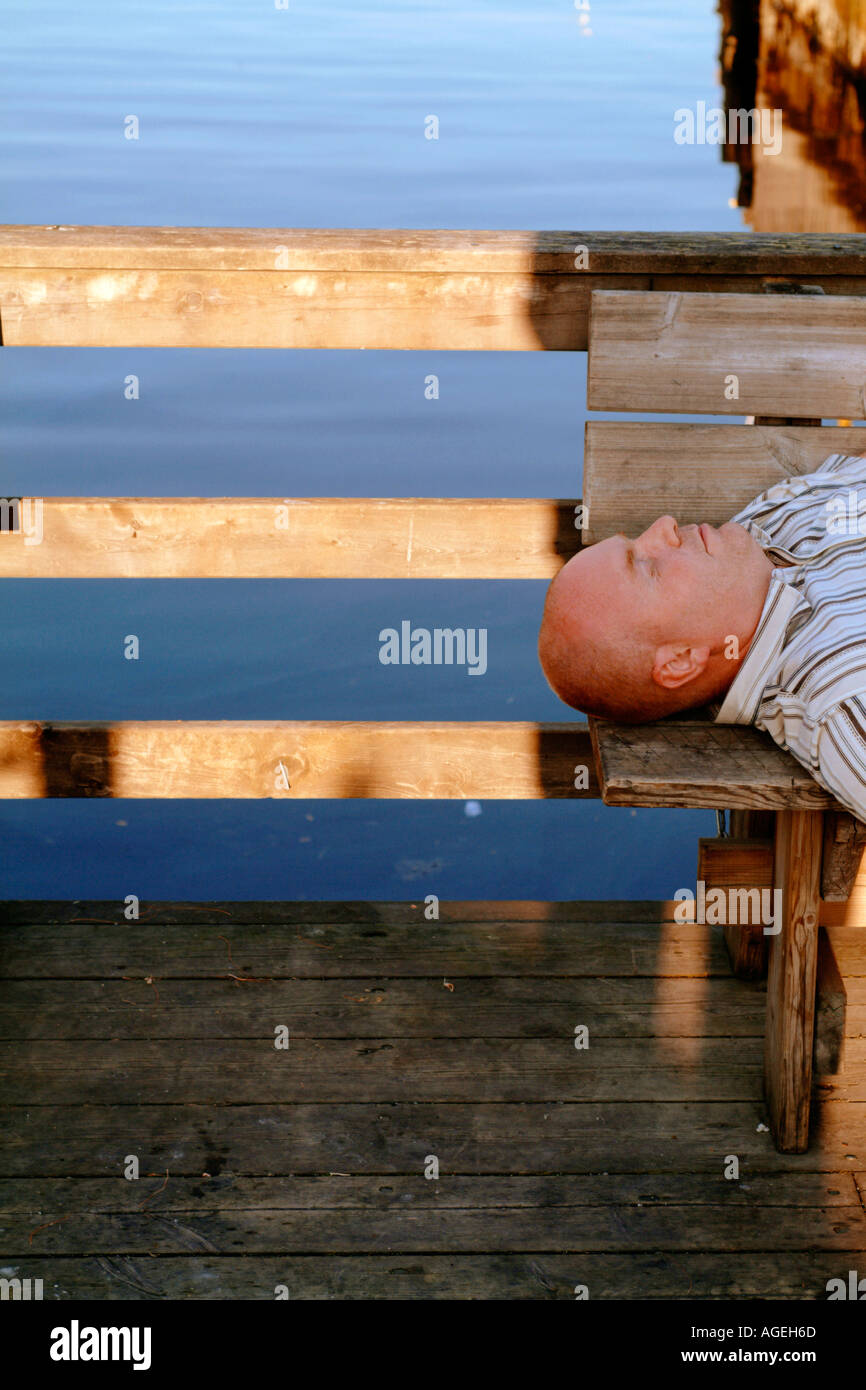 a man laying on a bench in the summer Stock Photo - Alamy