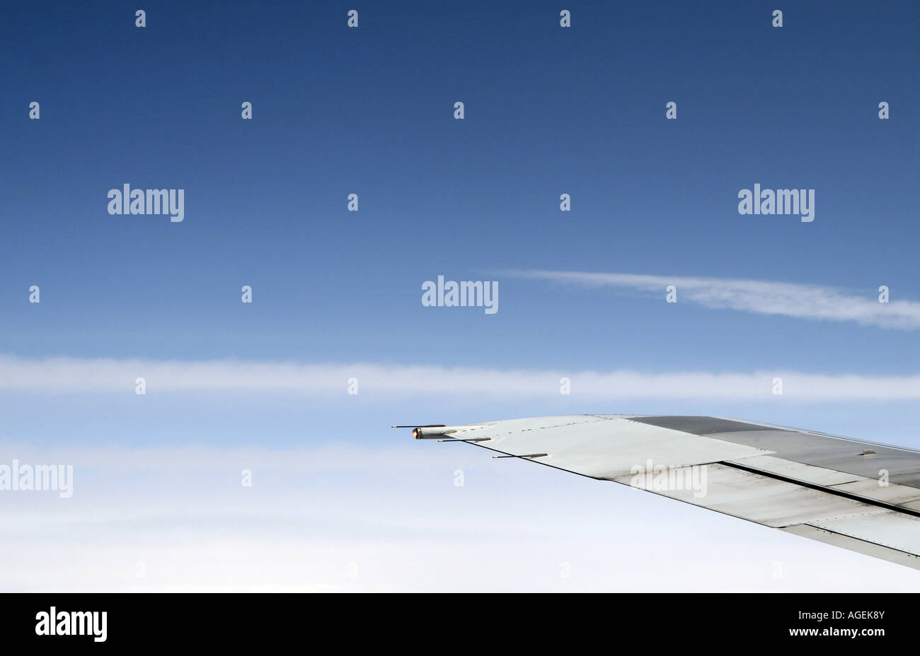 Sky clouds and an airplane wing seen through a window while flying ...
