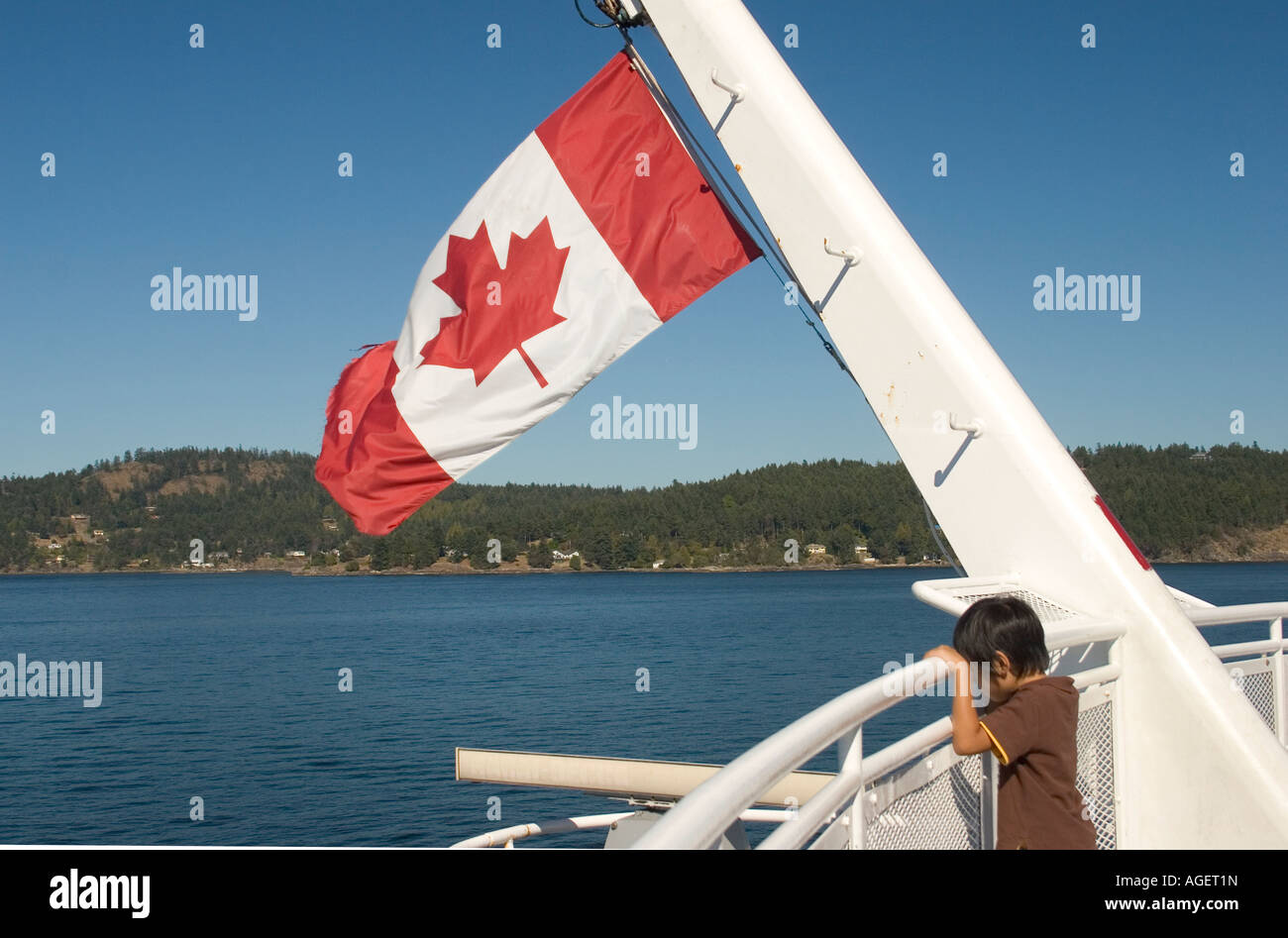 Asian boy at the rear of a British Columbia ferry with Canadian flag ...
