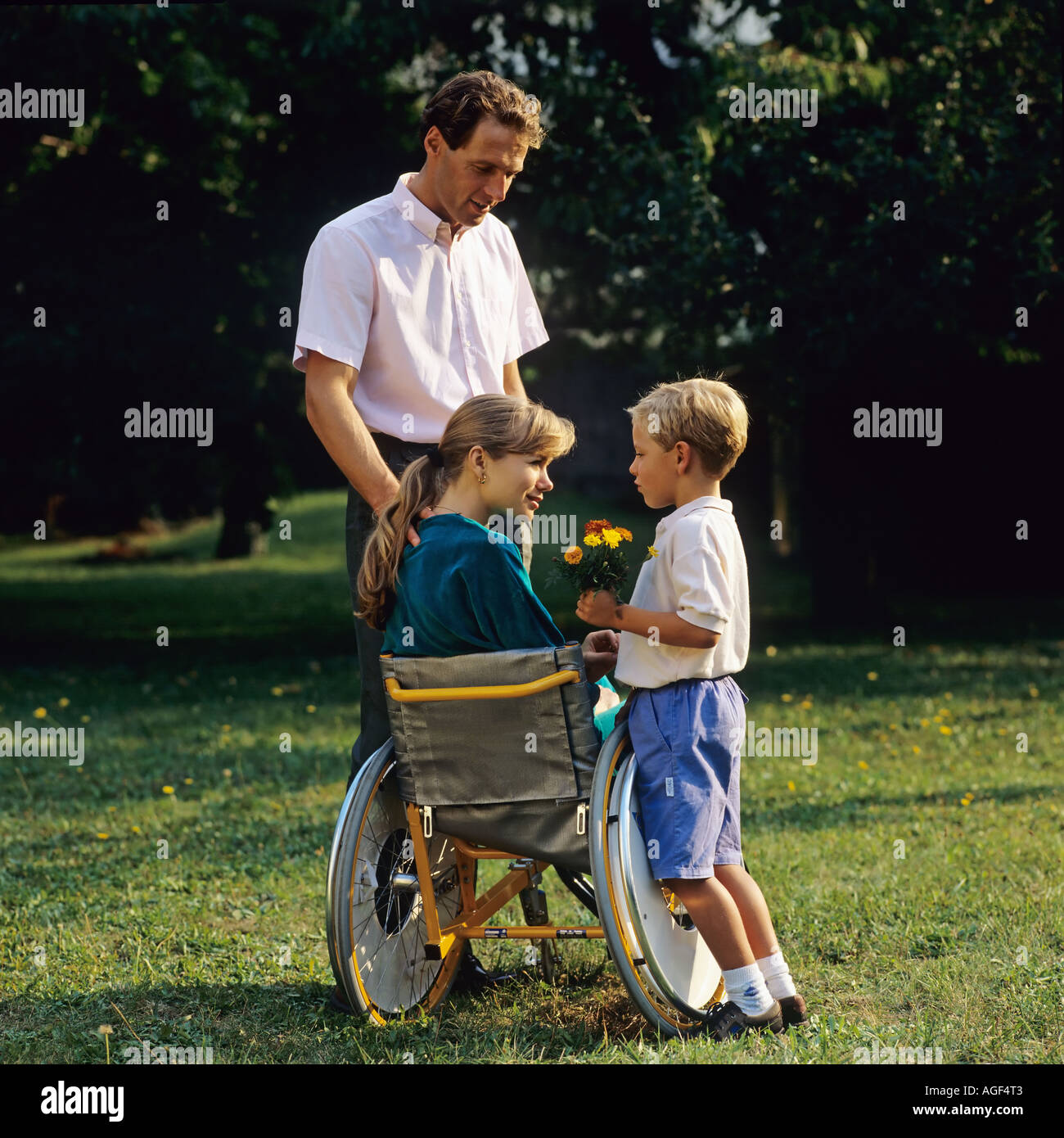 Little boy giving flowers to disabled woman in wheelchair and man in ...