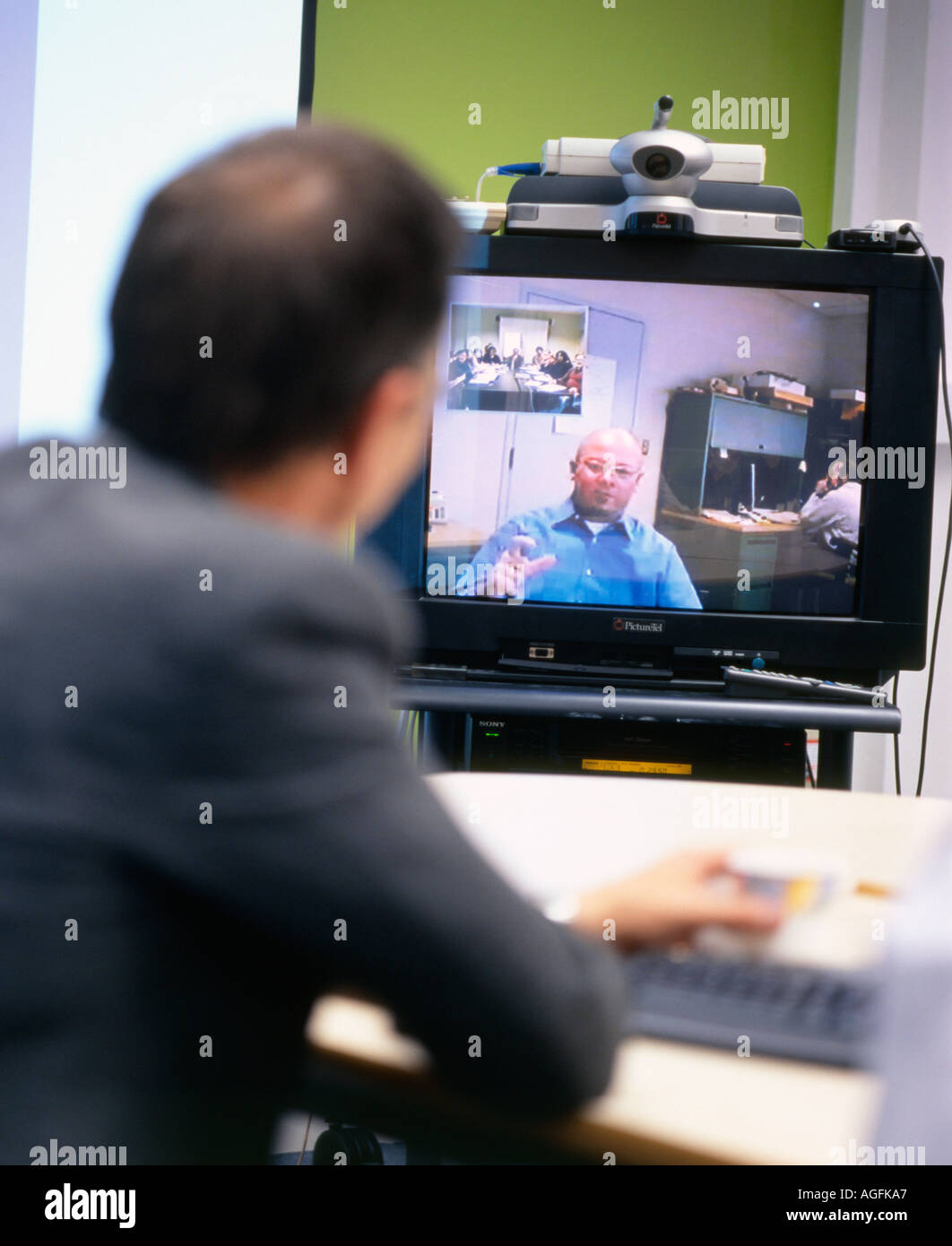 A modern video conference scene looking over the shoulder of a manager ...