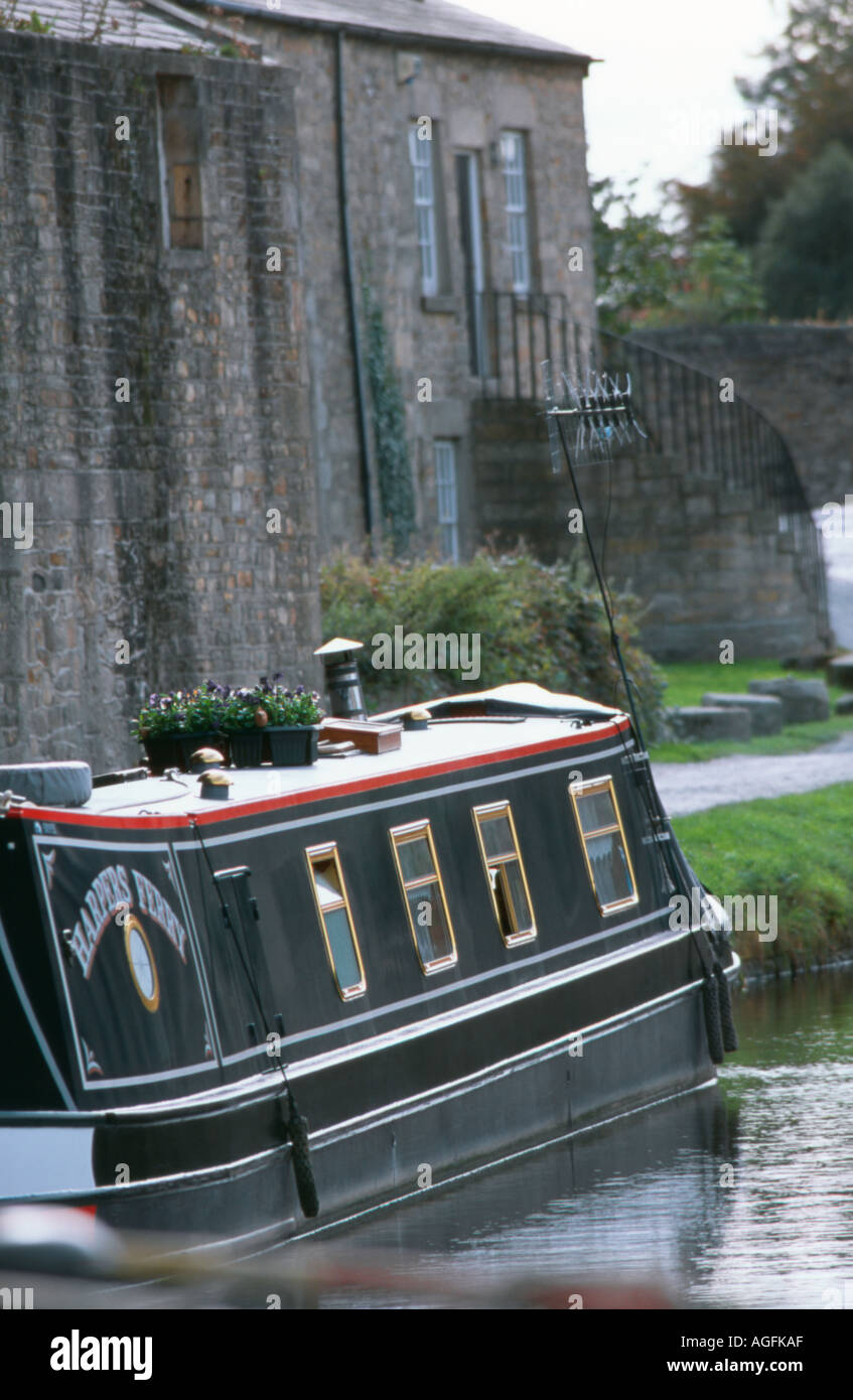 A typical English canal scene with a long barge moored along a towpath ...