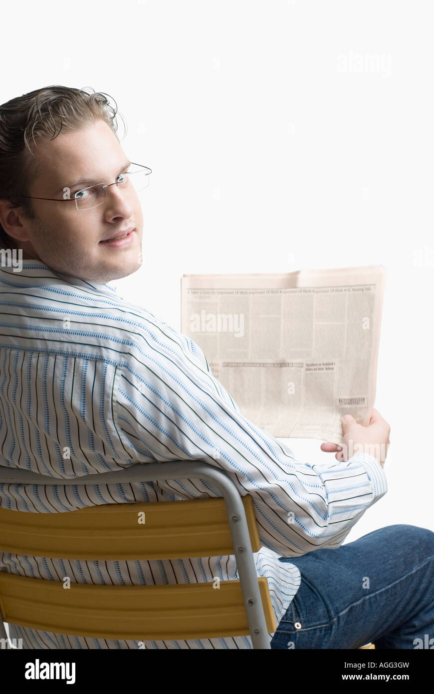 Portrait of a young man sitting on a chair and holding a newspaper ...