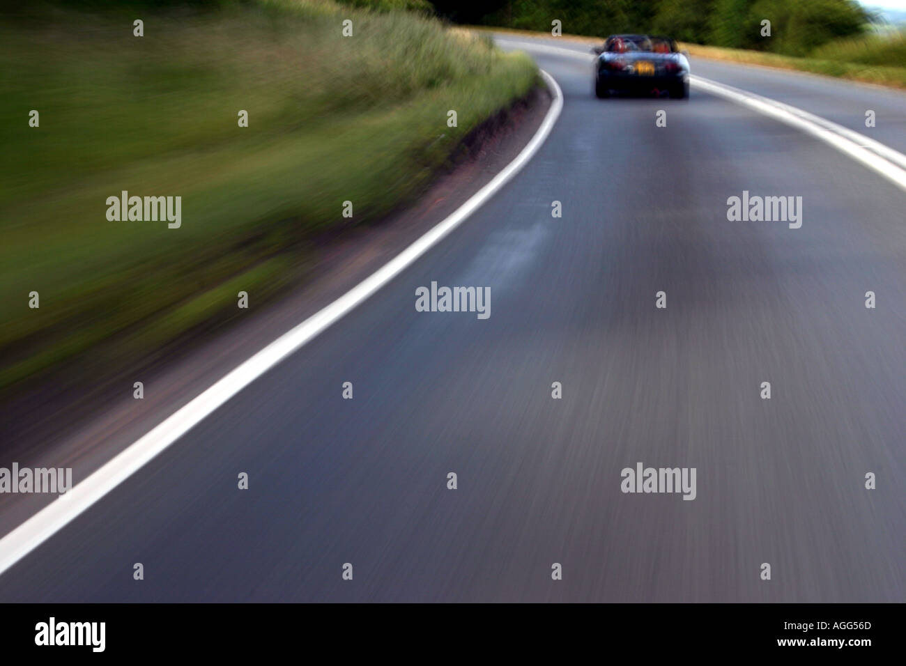 rear view of speeding sports car going round a bend Stock Photo - Alamy