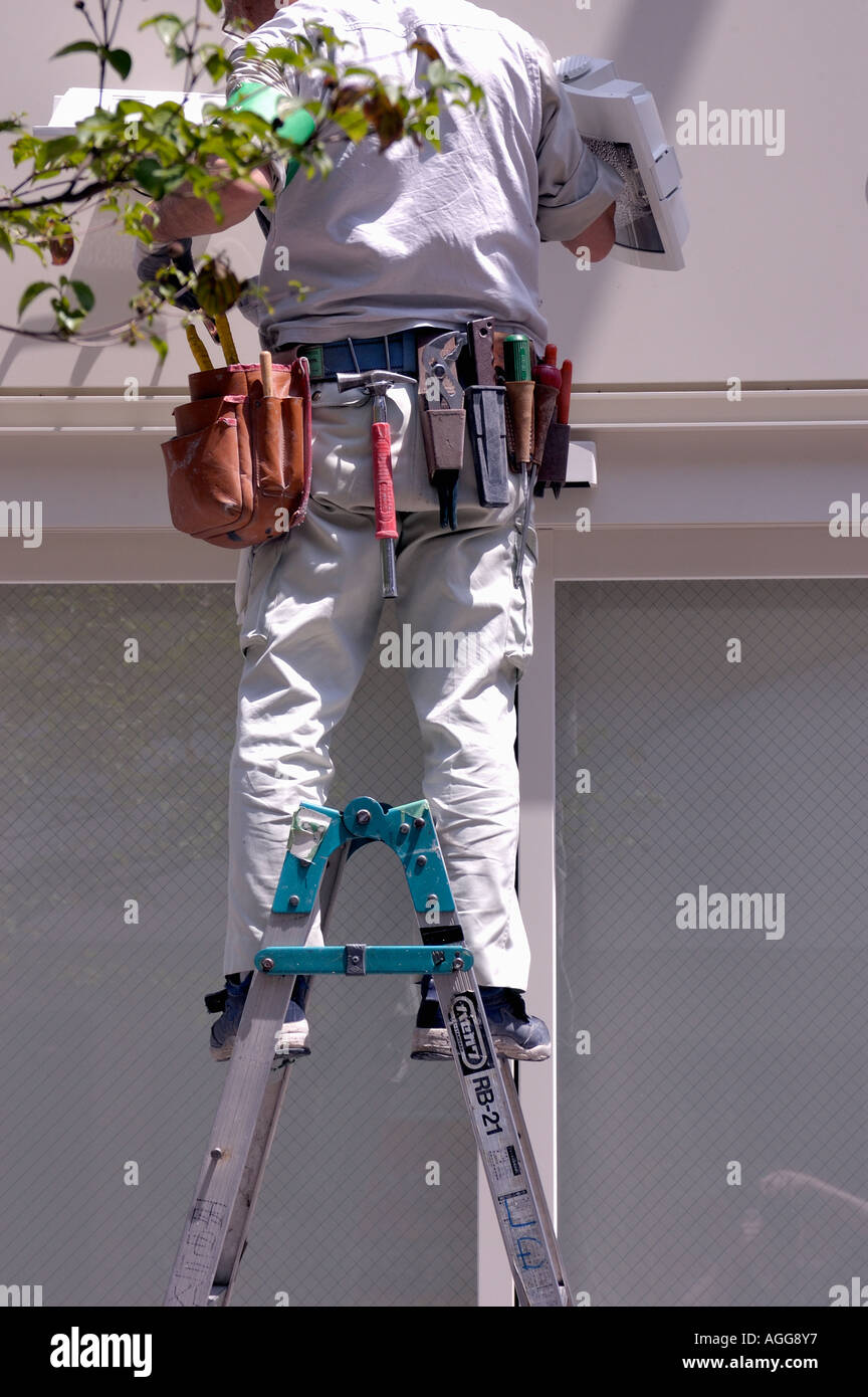 construction worker with tool belt balancing on a ladder, Tokyo, Japan ...