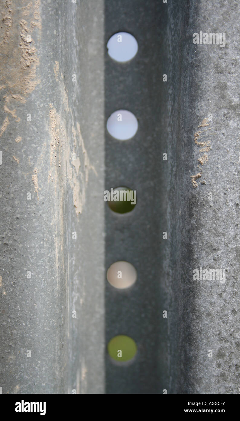 Gray metal sign post close up with holes showing green and blue ...