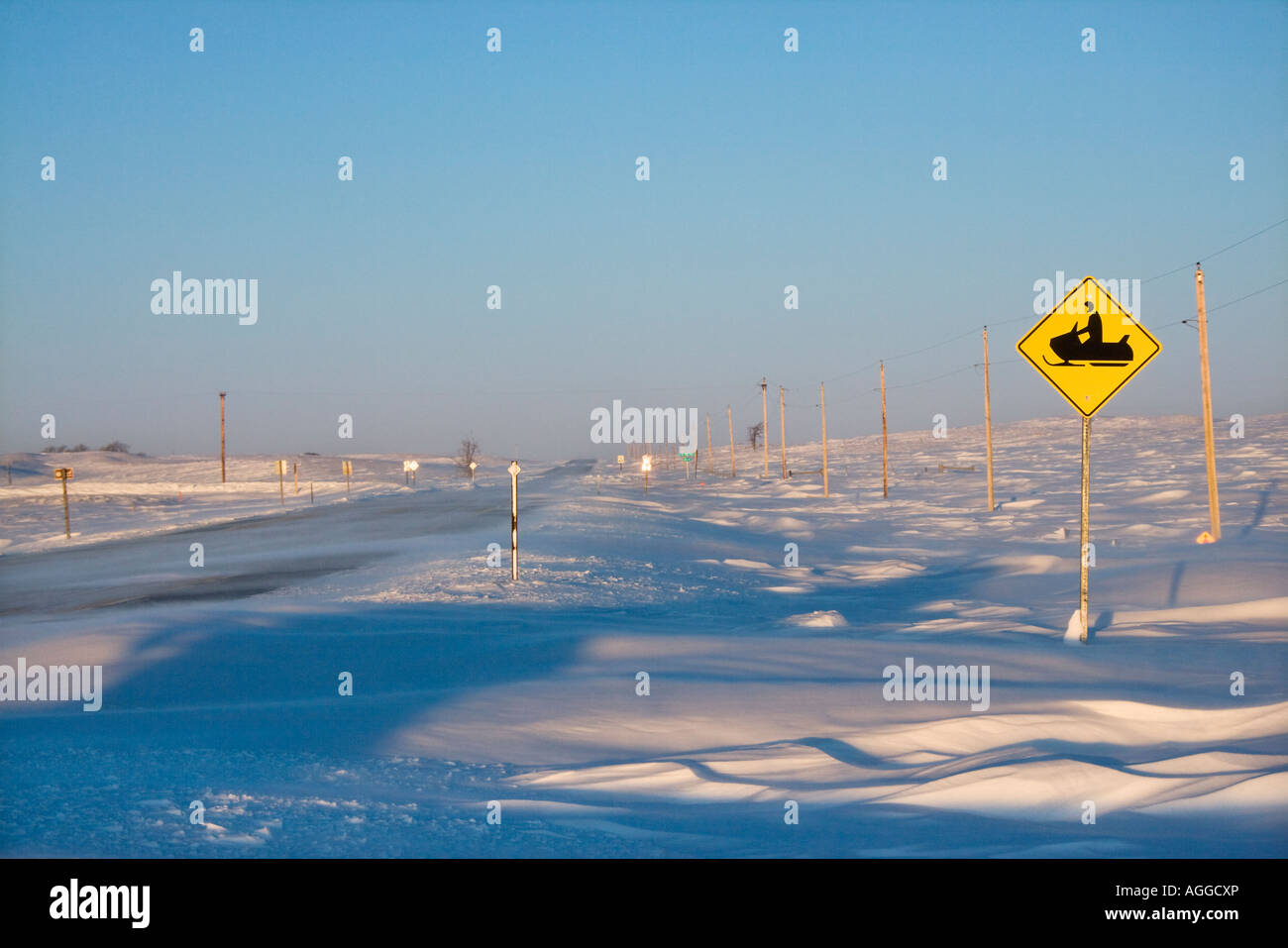 Snow covered road with snowmobile crossing sign Stock Photo - Alamy