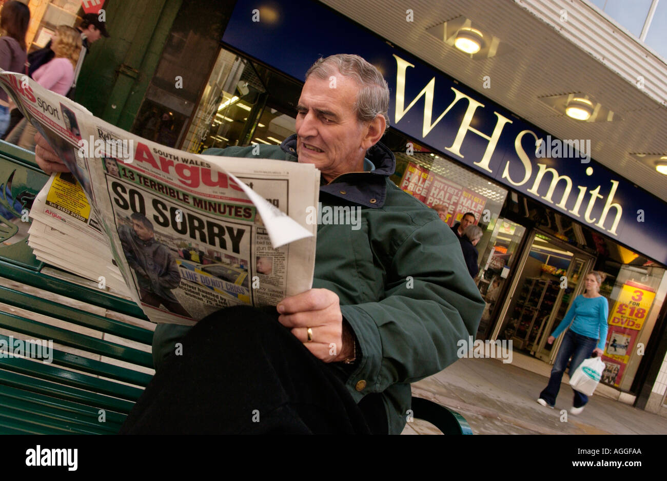 Man reading a newspaper on a bench in the pedestrian area outside WH ...