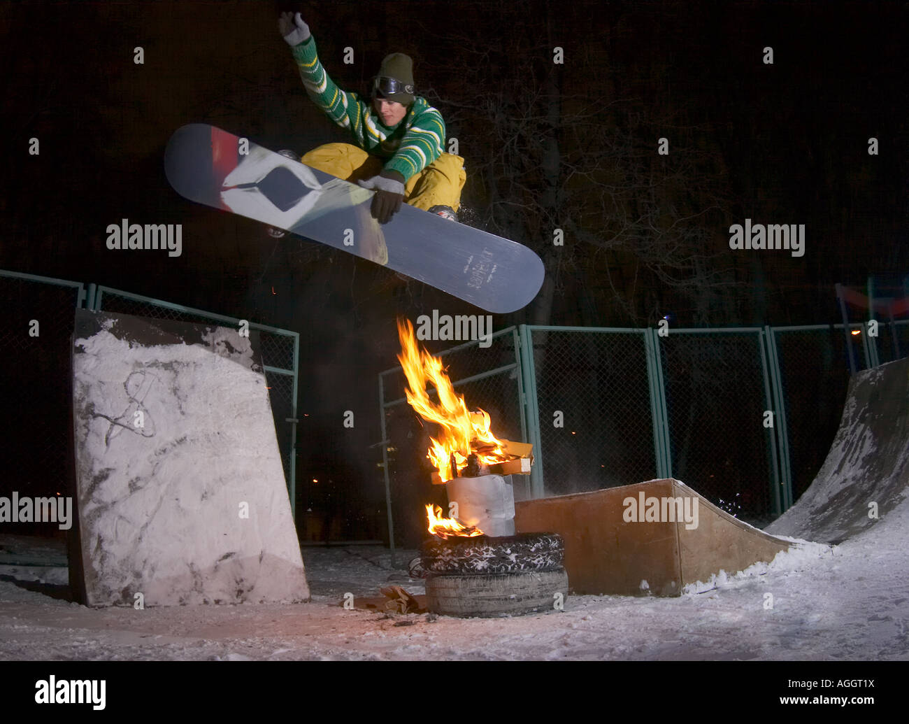 Snowboarder in the winter skate park in the city at night tricks and ...