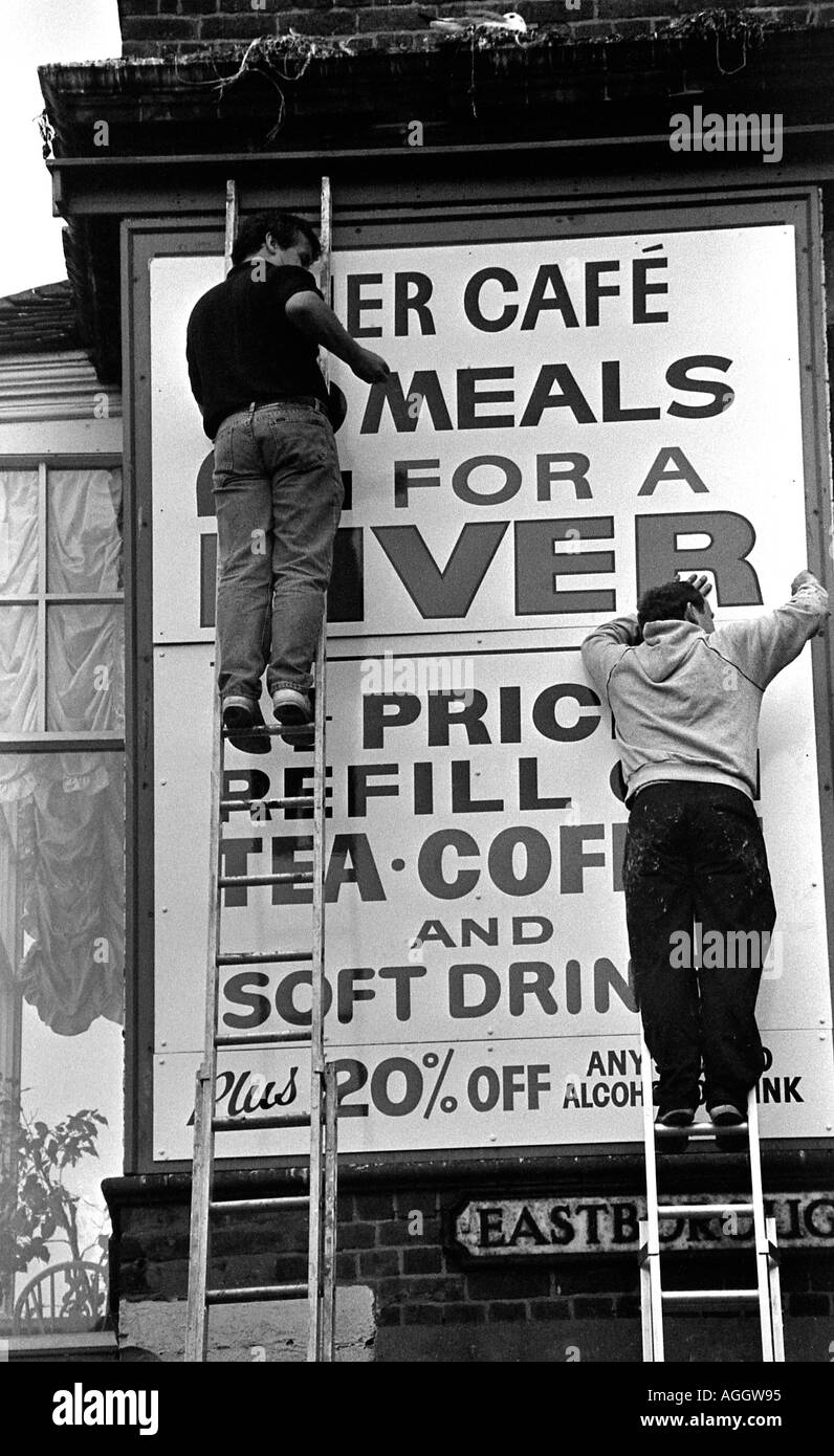 Two men fixing a poster to a display board Stock Photo - Alamy