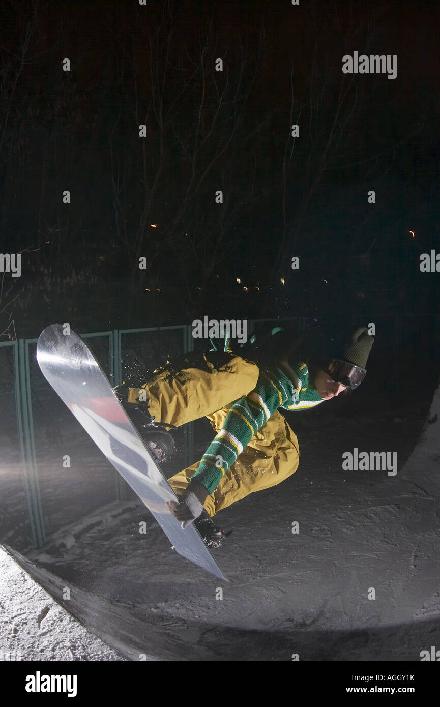 Snowboarder in the winter skate park in the city at night tricks and ...