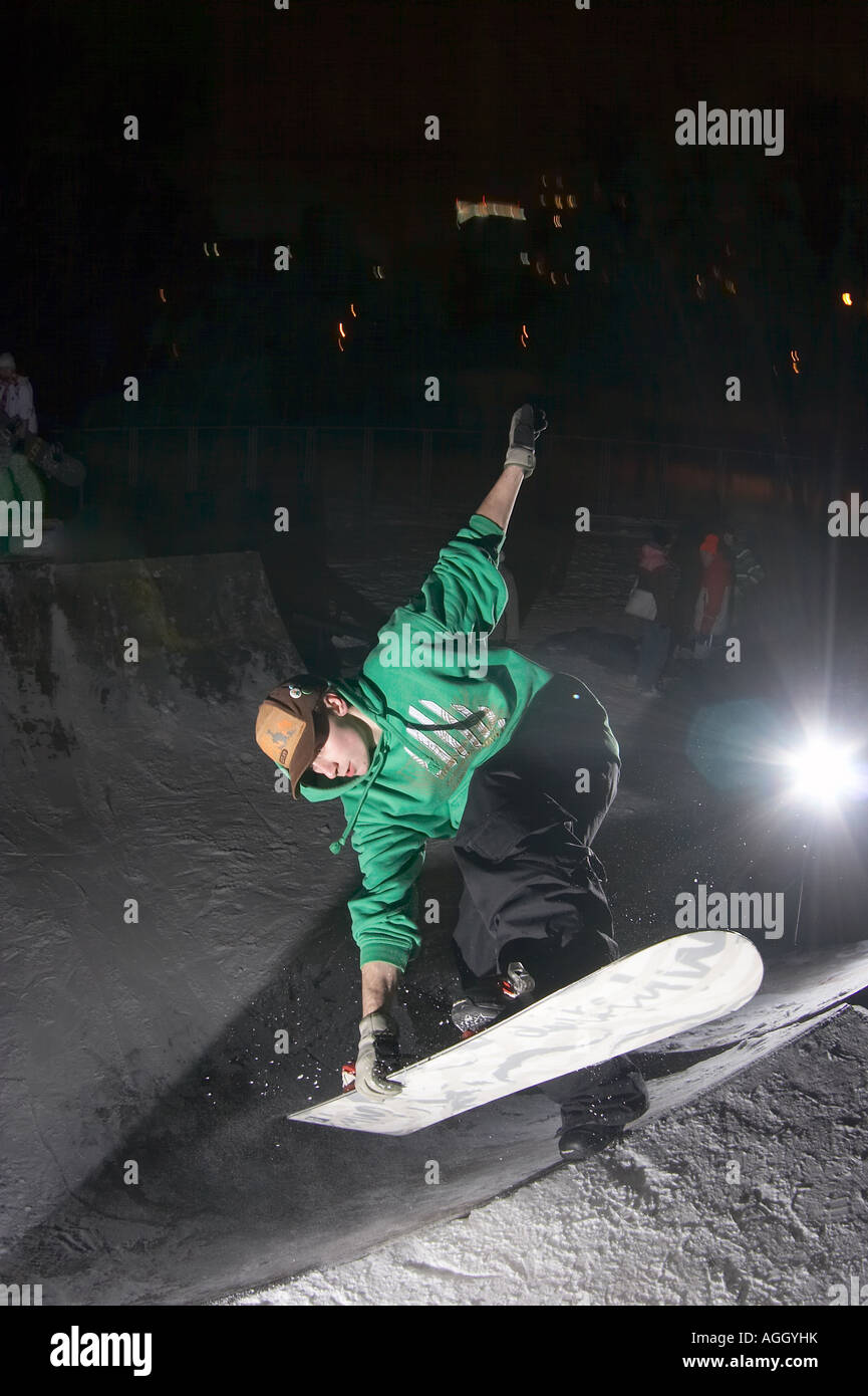 Snowboarder in the winter skate park in the city at night tricks and ...
