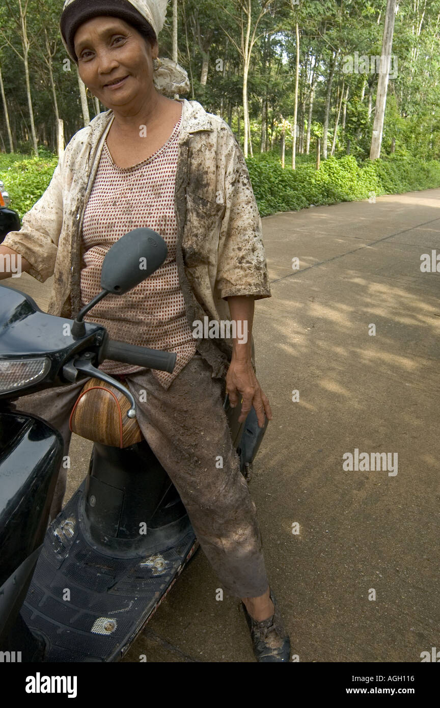 Thai rubber worker sits on a motorcycle after collecting raw rubber in ...