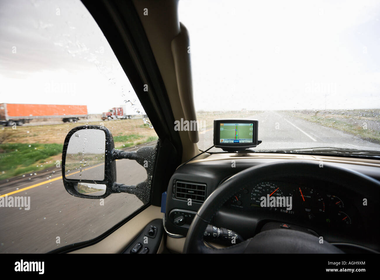 Vehicle dashboard with GPS and view through windshield of rainy highway ...