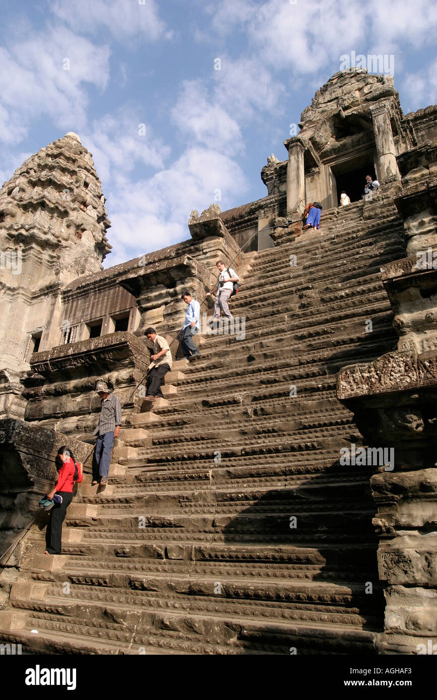 Tourists climbing down steep stairs on side of temple. Angkor Wat ...