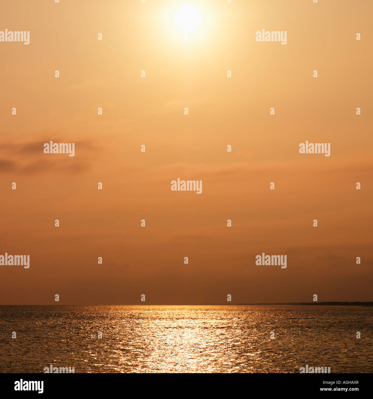 Sun over ocean with warm red tones Stock Photo - Alamy