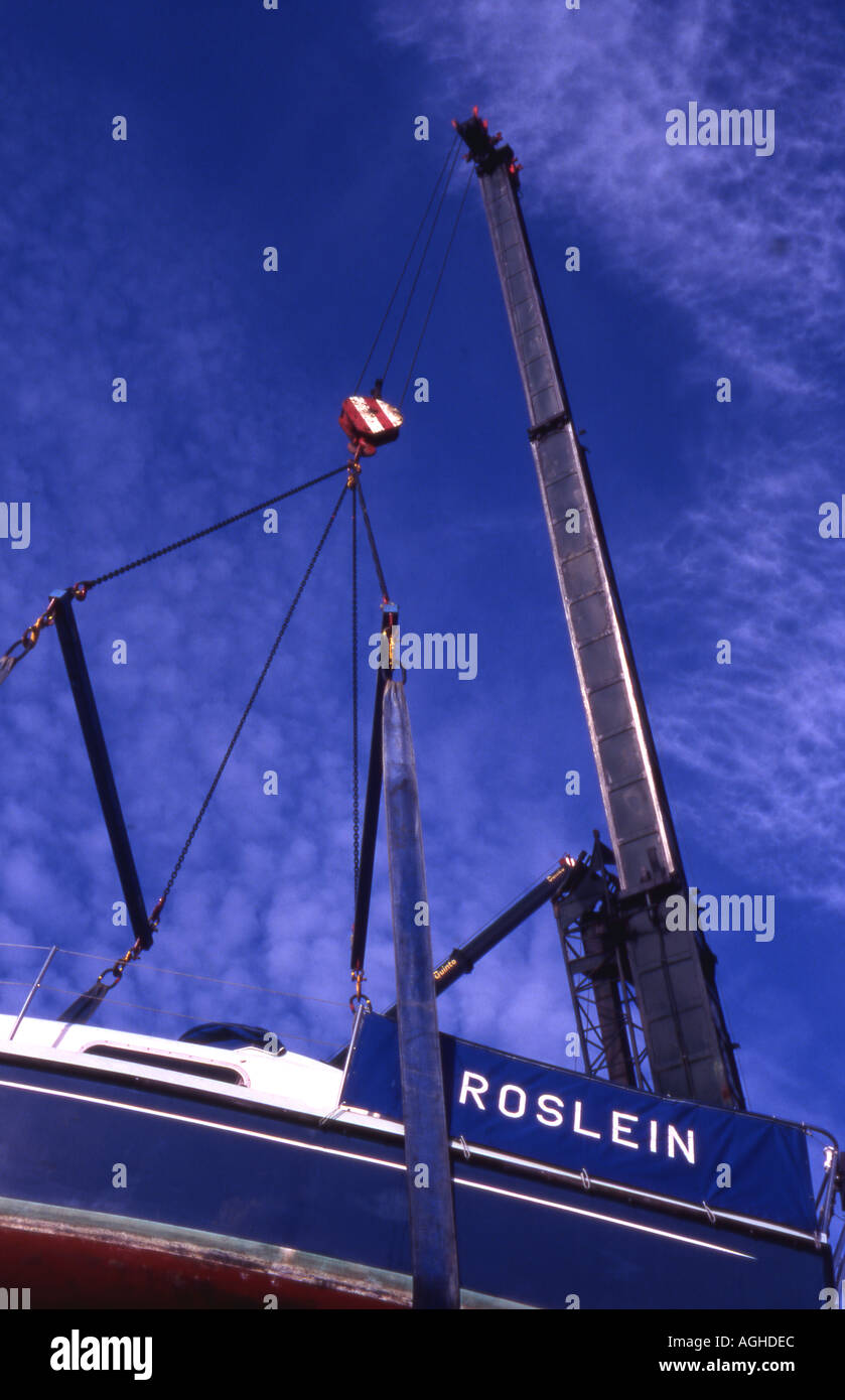 Crane lifting sailing boat out of water Stock Photo - Alamy
