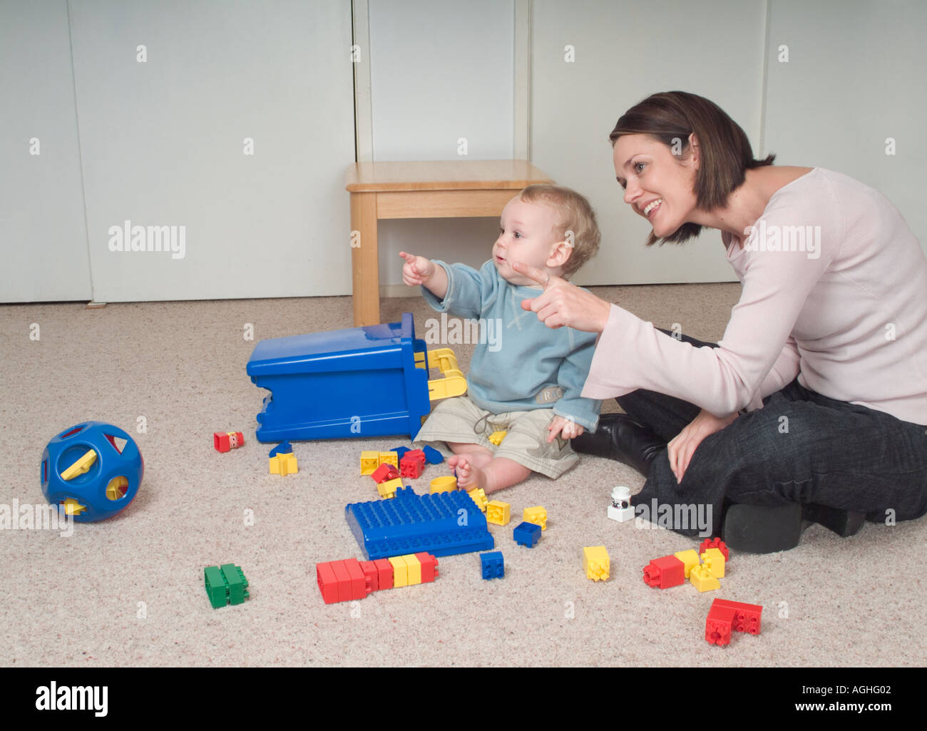 Mother and her baby son sitting on the floor The baby is imitating his ...